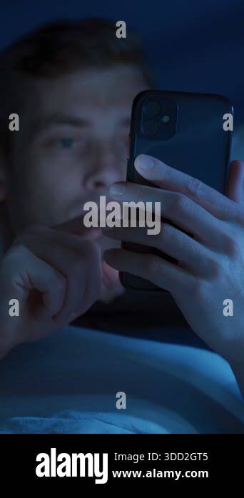 Late at night, tired man lying awake in bed, stares at his glowing ...