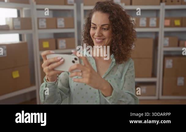 Woman holding smartphone, smiling and pumping fist amid parcel shelves ...