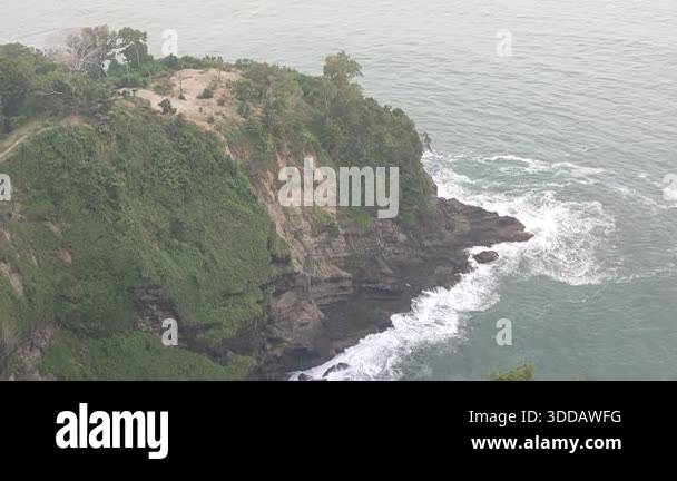 Coastal cliff covered in lush greenery with waves crashing below. Ideal ...