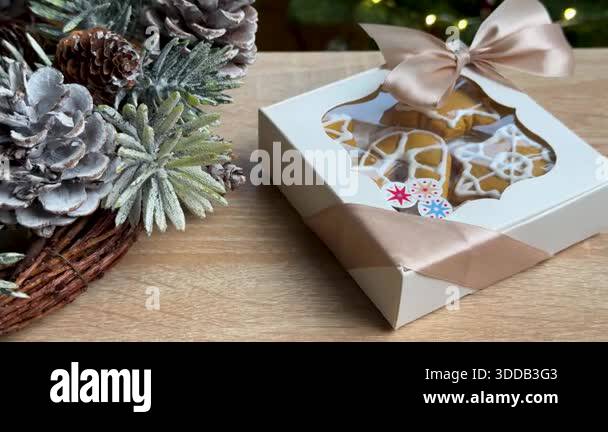 Gift box with decorated gingerbread cookies on a wooden table next to a ...