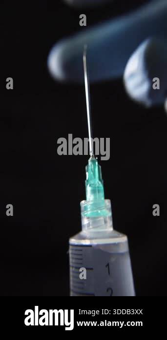 A medical professional uncapping a syringe needle before giving ...
