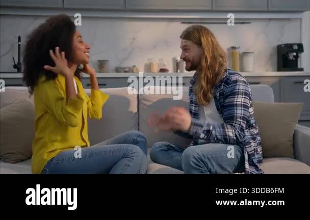 Happy excited multiethnic couple amazing news at home talking couch ...