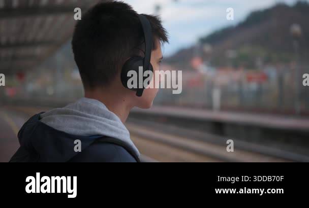 Close up side view of a teenage boy wearing headphones standing on a ...
