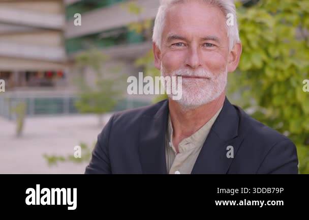 Zoom-in closeup shot of confident senior businessman smiling outdoors ...