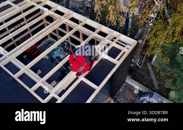 A person is creating a wooden structure on the top of a building during ...
