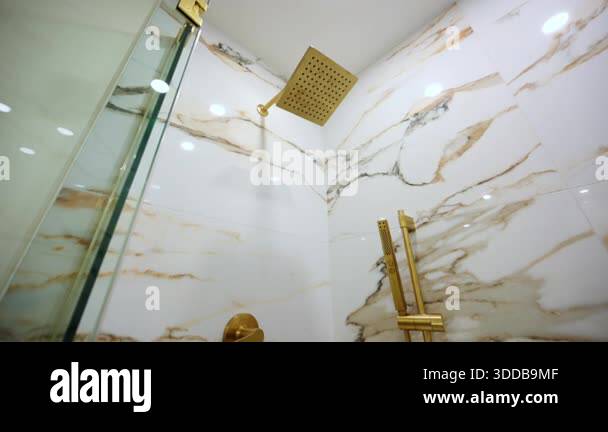 Luxury bathroom shower with elegant gold fixtures. The marble-style ...