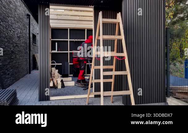 Workers construct a storage shed in a backyard using wood and tools ...