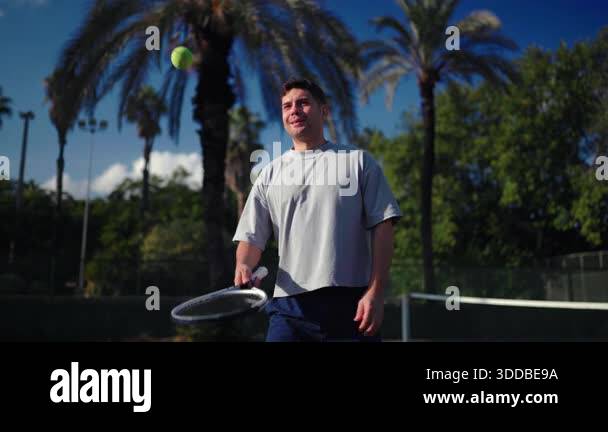 Relaxed male tennis player balancing ball on racket during outdoor ...