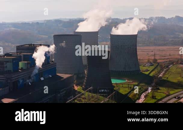 Aerial drone view of several large cooling towers releasing steam into ...