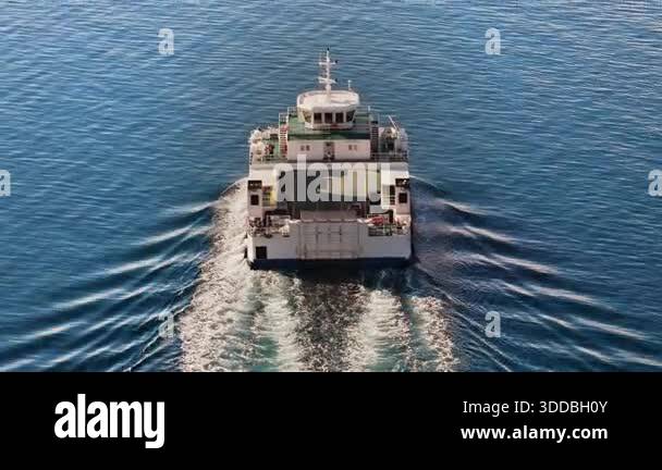 Aerial drone view of a ferry traveling across smooth blue water ...