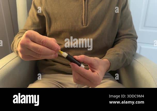 Man with diabetes mellitus carefully loading a new sterile lancet into ...