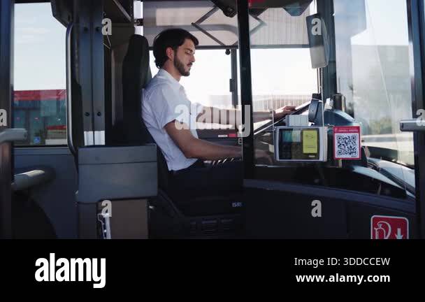 Young handsome bus driver in uniform sitting behind the steering wheel ...