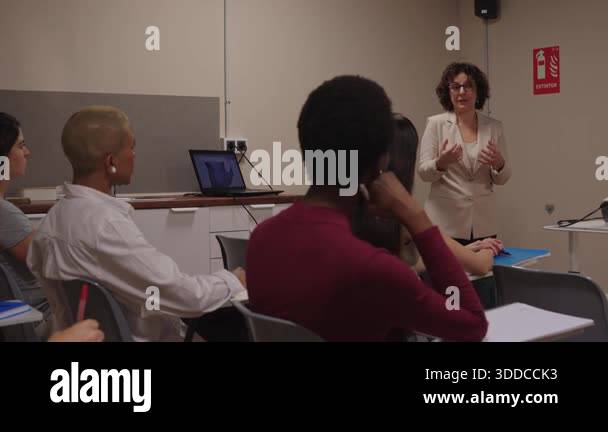 Female professor teaching a diverse group of college students in a ...