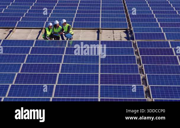 Three renewable energy engineers discussing project plans on a rooftop ...