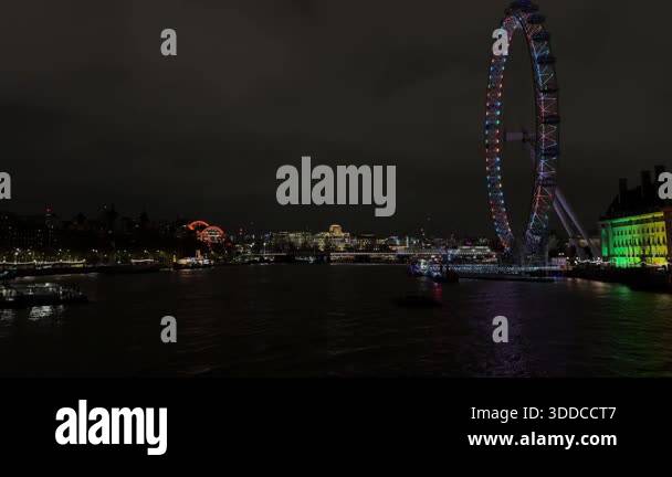 Iconic london eye turning at night with colorful lights reflecting on ...