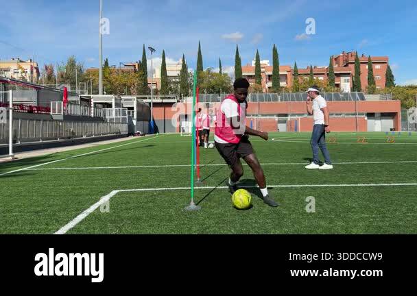 Young athletic man skillfully dribbling a soccer ball around a training ...