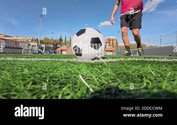 Slow motion, low angle view of a football player kicking a soccer ball ...