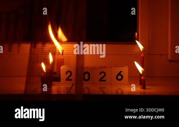 Cubes with the number 2026 and burning candles on a windowsill in a ...
