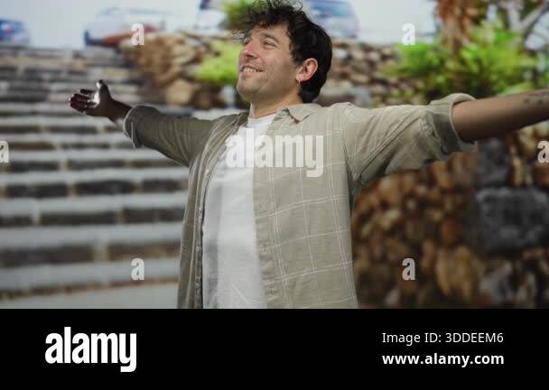 Hispanic man with arms outstretched smiling joyfully on an outdoor ...
