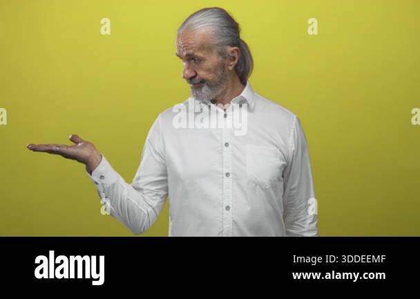 Man with hoary ponytail and beard holds out open left hand palm up in ...