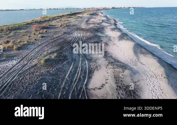 Birds eye view of narrow empty quiet beach with dry sand right and ...