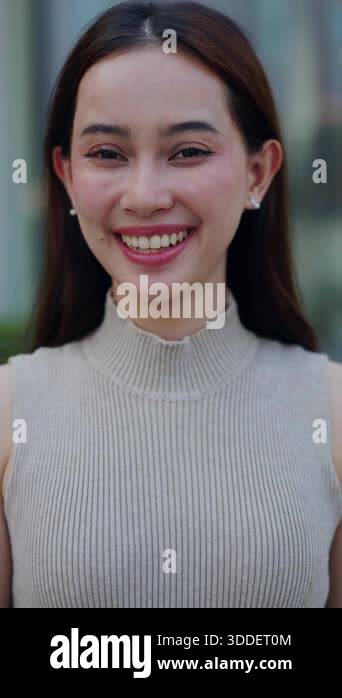 Closeup portrait of pretty Asian woman in grey high-neck top smiles on ...