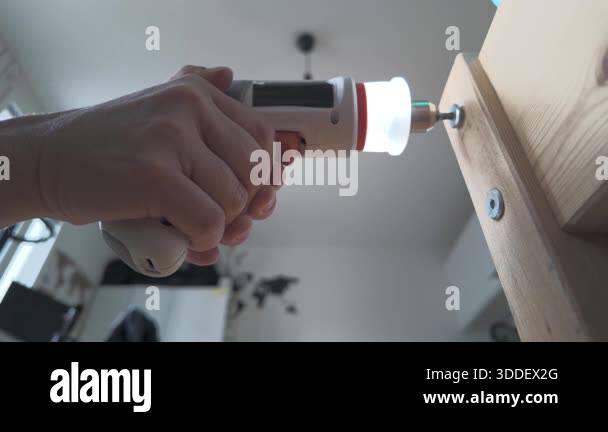 Upward angle showing a cordless electric screwdriver removing a screw ...