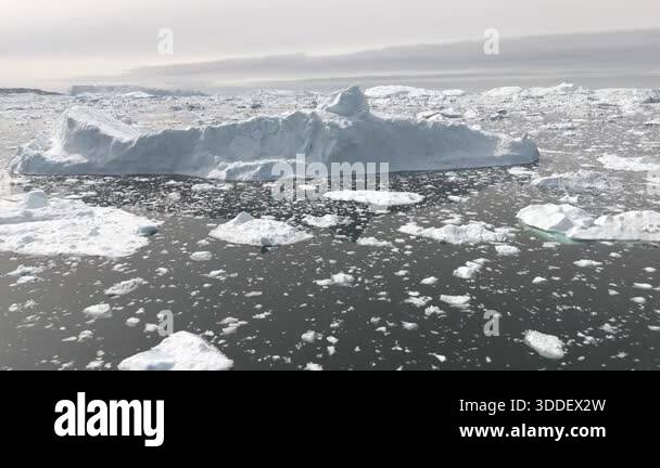 Horizontal drone panorama rotates around a colossal iceberg surrounded ...