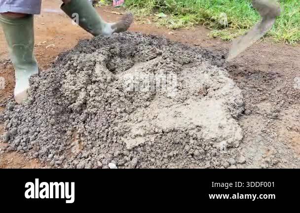 Close up of a construction worker mixing sand and cement manually with ...