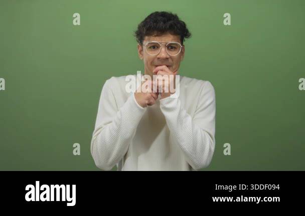 Young hispanic man biting fingernails with tense face in green studio ...