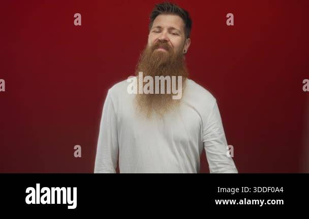 Young caucasian man with long beard smiling and pointing finger to head ...