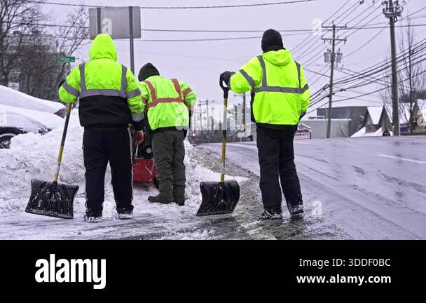 NORWALK, CT, USA - DECEMBER 27, 2025: Workers use shovels and ...