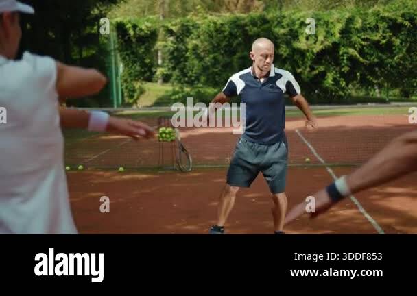 Slow motion young players warm up before a game of tennis with trainer ...