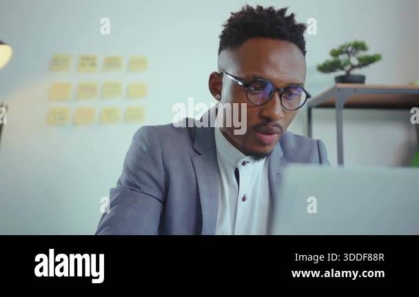 Smiling African American handsome man uses computer for work in modern ...
