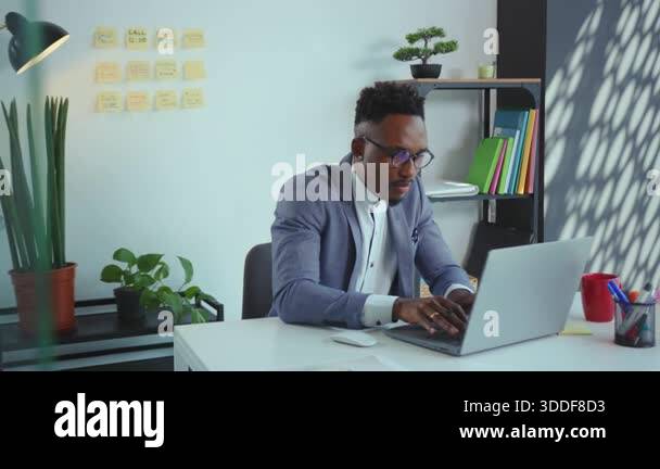African American handsome male uses computer for work in modern office ...