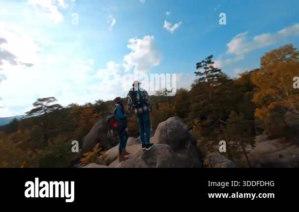 FPV footage of young active hikers couple climbing on rocks to observe ...