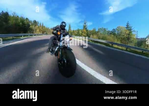 Wide-angle motion footage of fast motorbike driver riding on highway ...