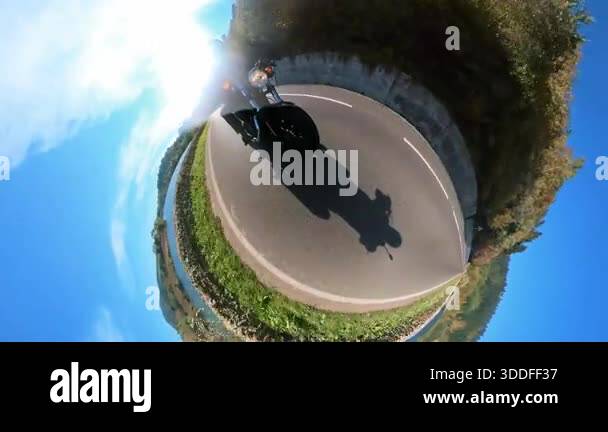 Biker in wideangle view riding highway road alone on bright sunny day ...