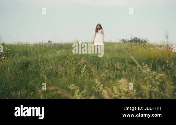 Shot of marvelous elegant lady in dress walking through field and ...