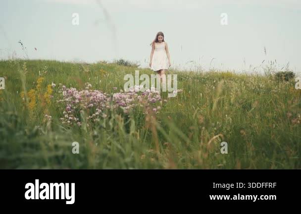 Harmonious smiling Caucasian girl in white romantic dress raising hands ...