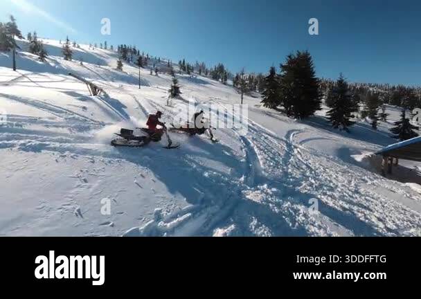 In winter mountains, guys on snowmobiles jump and ride in the winter at ...