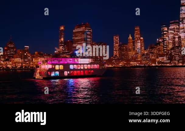 A boat with colorful lights floats on the water near New York City at ...