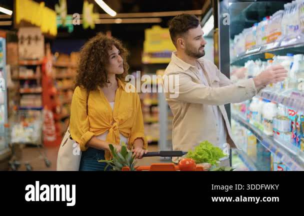 Happy young couple shopping for groceries at the supermarket. The man ...