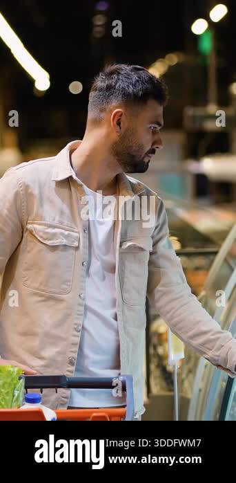 Handsome young man selecting fresh fish from a refrigerated display in ...
