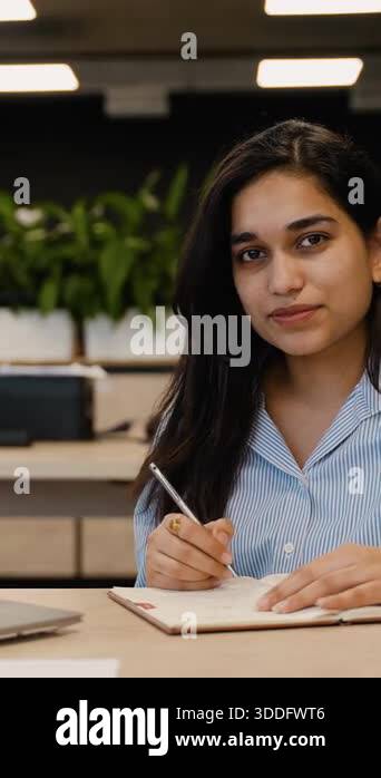 Portrait of a smart indian woman writing in a notebook while studying ...