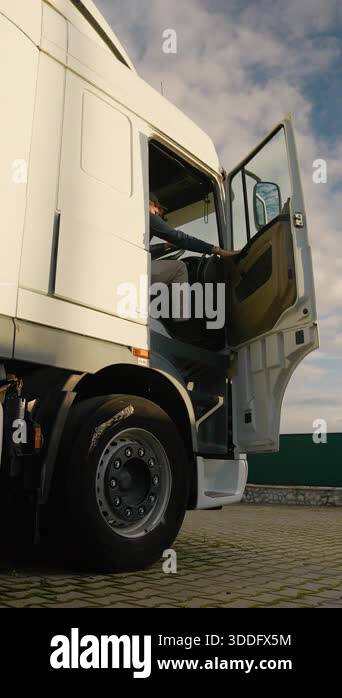 Professional truck driver getting out of his white semi trailer truck ...