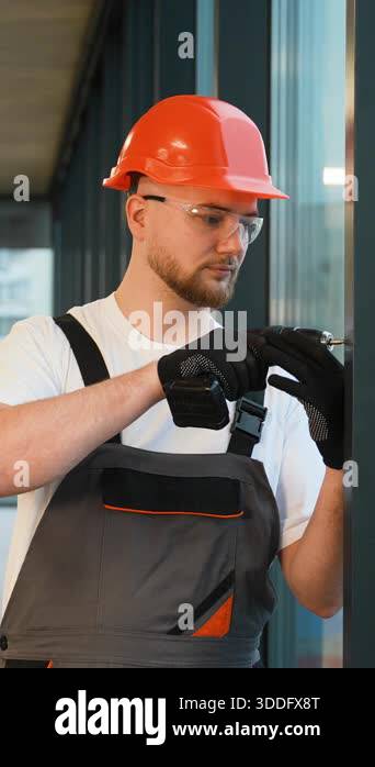 Young male builder wearing a hard hat, safety glasses, and overalls ...