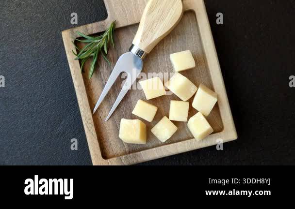 Cubed cheddar, gouda, or parmesan cheese on a cutting board. Cubed ...