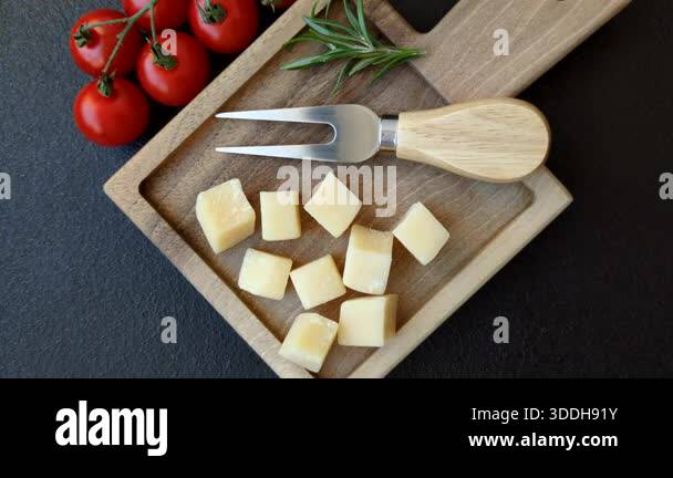 Cubed cheddar, gouda, or parmesan cheese on a cutting board. Cubed ...