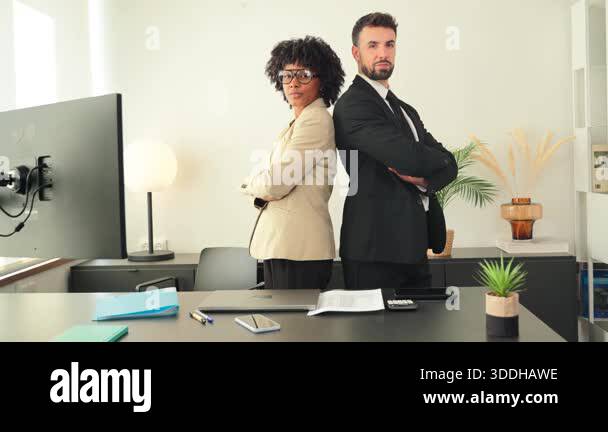 Dynamic business partners exude confidence while standing back to back ...
